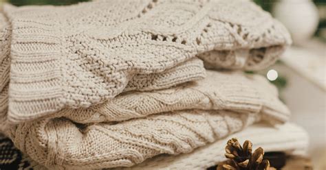 조명과 흰색 별의 크리스마스 트리 배경에 솔방울이 있는 소박한 나무에 아늑한 니트 스웨터 축제 장식 스칸디나비아 방에 세련된 스웨터 더미 겨울 방학 사진