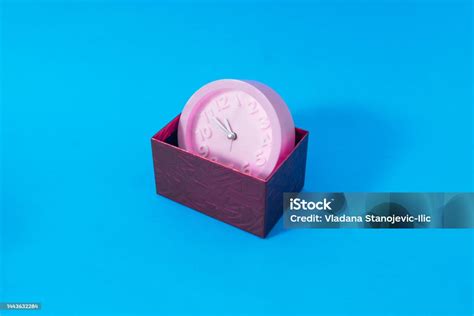 파란색 배경에 진한 빨간색 상자에 자정을 보여주는 분홍색 시계 2023년 새해 또는 시즌 인사말 카드 또는 웹 배너를 위한 최소한의 디자인 공간을 복사합니다 0명에 대한