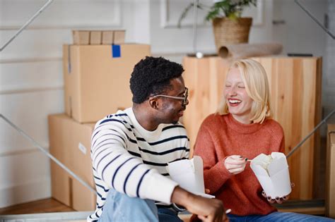 젊은 부부는 그들 주위에 제거 상자와 테이크 아웃을 먹고 바닥에 앉아 새로운 집으로 이동 축하 이주 개념에 대한 스톡 사진 및 기타 이미지 Istock