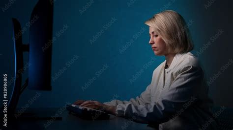Side View Of Focused Female Hacker Hacking Into Secure System In Dark Room With Cozy Neon