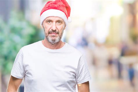 중 년 노인의 수석 남자 얼굴에 심각한 표정으로 격리 된 배경 위에 크리스마스 모자를 쓰고 간단 하 고 카메라를 보고 자연 T 셔츠에 대한 스톡 사진 및 기타 이미지