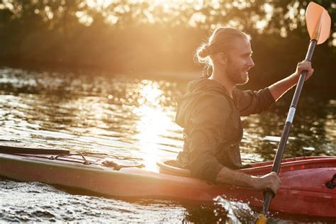 행복한 백인 청년은 여름 오후에 자연으로 둘러싸인 호수에서 카약을 타고 노를 저어 쾌활한 모습으로 보입니다 래프팅에 대한 스톡 사진 및 기타 이미지 Istock