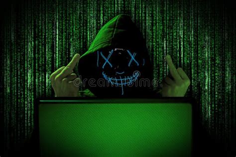 Hacker With Blue Glowing Mask Behind Notebook Laptop In Front Of Green