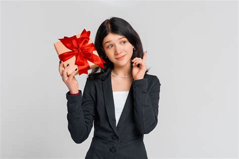 사려 깊은 갈색 머리 십대 소녀는 선물을 들고 손가락을 들어 올리는 동안 해결책을 실현하고자하는 흰색 배경 위에 서 휴일 축하 및 생일 개념 갈색 머리에 대한 스톡 사진 및