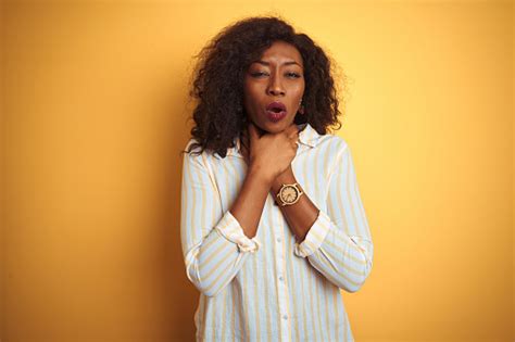 고립 된 노란색 배경 위에 서있는 줄무늬 셔츠를 입은 아프리카 계 미국인 여성이 고통스러운 목졸림 때문에 외치고 질식합니다 건강 문제 질식 과 자살 개념 건강관리와 의술에