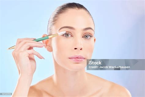 메이크업 초상화 그리고 화장품과 스킨케어를 위한 파란색 배경에 눈에 붓을 든 여자 마스카라 도구 속눈썹과 자연의 아름다움 스튜디오에서 속눈썹에 눈 제품을 바르는 모델의 얼굴