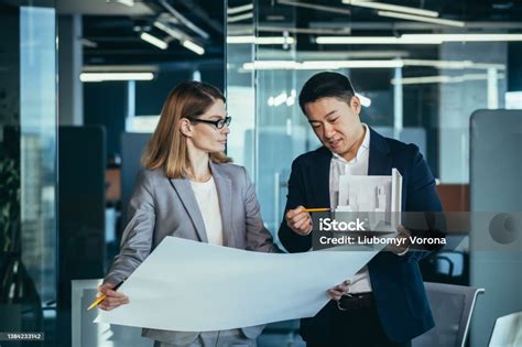 그룹 젊은 크리에이티브 엔지니어 개발자는 청사진을 읽고 사무실에 서 새로운 프로젝트를 논의 모델 빌딩을 이용한 아시아 남녀 동료와 대화하는 팀 건축가 디자이너 건설 산업에