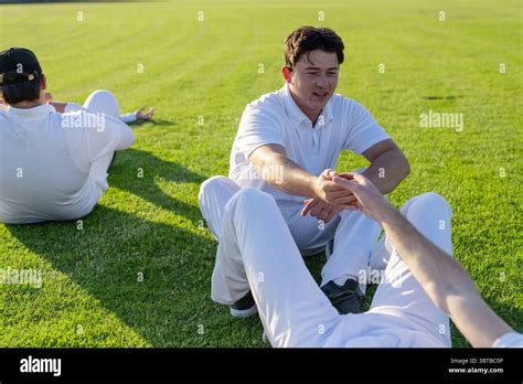Diverse Male Teammates Performing Partner Sit Up Exercises On Grass