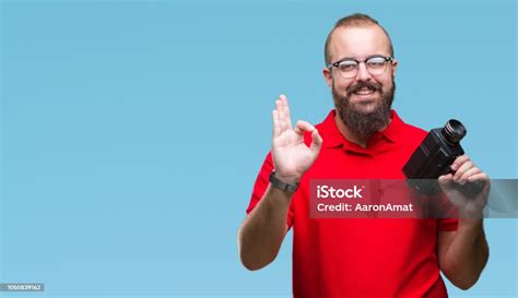 젊은 백인 Hipster 남자 Filmming 레트로 비디오 카메라를 사용 하 여 손가락 우수한 기호 확인 서명 하 고 격리 된 배경 위에 개념에 대한 스톡 사진 및 기타