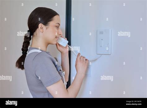 Teenage Girl Holding Intercom Handset While Talking To Guest Stock