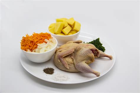 건강한 수프를 요리하기위한 재료가있는 신선한 생 유기농 메추라기 고기 생 메추라기 새 신선한 감자 당근 양파 냉동 파슬리 및 향신료를 흰색 배경에 흰색 접시에 대고 건강한