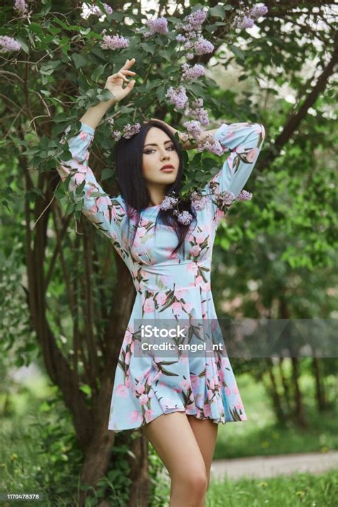 아름다운 꽃 나무의 가지에서 갈색 머리 여자입니다 소녀 몸에 짧은 여름 드레스 공원에서 봄 산책 낭만적 인 분위기 덤불과 나무 근처 소녀의 초상화 갈색 머리에 대한 스톡