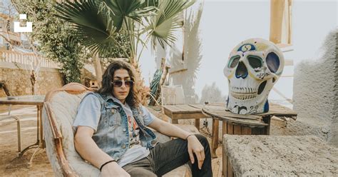 배경에 해골이 있는 의자에 앉아 있는 남자 사진 Unsplash의 무료 사람의 이미지