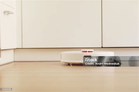 백색 로봇 진공 청소기는 이물질에서 바닥을 청소하고 전기 진공 청소기 진공 청소기 전기 로봇 청소 기술 로봇 진공 청소기의 상단보기로 집 청소하십시오 가구에 대한 스톡 사진