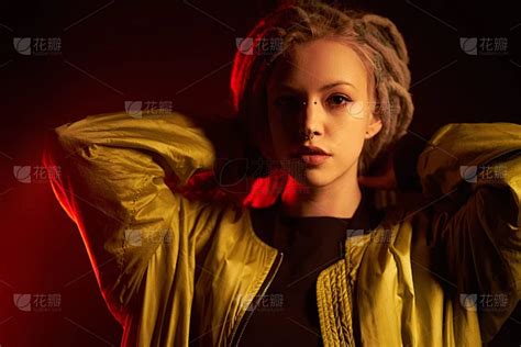 漂亮的女孩，梳着发辫，戴着耳环。在多色光的照射下，红色和黄色的人像上有黑色的背景色光人像素材 花瓣网