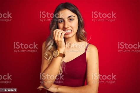 빨간 고립 된 배경 위에 티셔츠를 입고 젊은 아름다운 여자는 손톱을 물고 입에 손을 긴장 찾고 불안 문제 스튜디오 촬영에 대한 스톡 사진 및 기타 이미지 Istock