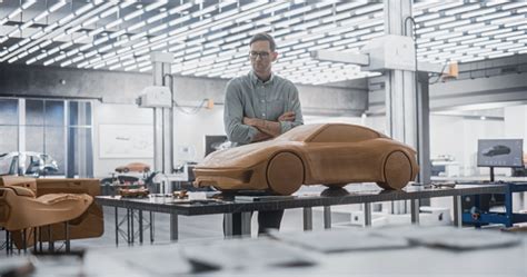 주걱을 사용하여 폴리머 모델링 점토로 프로토타입 자동차를 만드는 자동차 디자이너 차량 생산 공장의 연구 개발 스튜디오에서 일하는 집중 모델러 3차원 형태에 대한 스톡 사진