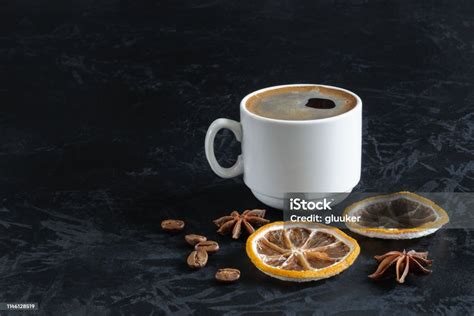 말린 레몬 슬라이스 스타 아니 스 커피 원두가 있는 흰 컵에 거품을 낸 갓 내린 커피를 복사 공간과 함께 검은 색의 콘크리트