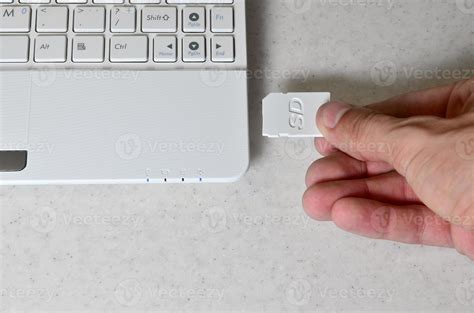A Male Hand Inserts A White Compact SD Card Into The Corresponding Input In The Side Of The