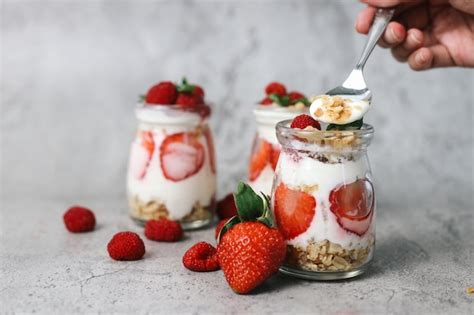 Premium Photo Hand Holding Spoon With Parfait Made From Strawberries Yogurt And Granola Over