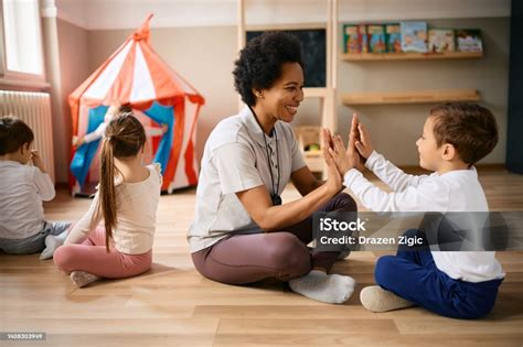 행복한 흑인 체육 선생님과 유치원에서 운동 수업 중에 재미있게 지내는 작은 소년 교사 교육 관련 직업에 대한 스톡 사진 및 기타