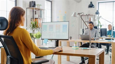 Over The Shoulder Female Mobile Software Developer Sitting At Her Desk