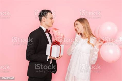 우아한 남자는 양복에 분홍색 바탕에 아름 다운 여자에 게 꽃의 꽃다발과 선물 상자를 제공 합니다 여자의 일 기업 비즈니스에 대한 스톡 사진 및 기타 이미지 Istock