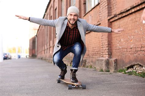 도시의 거리에 롱 보드에 회색 코트와 모자에 잘생긴 젊은 남자 도시 스케이트 보드 개념입니다 거리에 대한 스톡 사진 및 기타 이미지 Istock