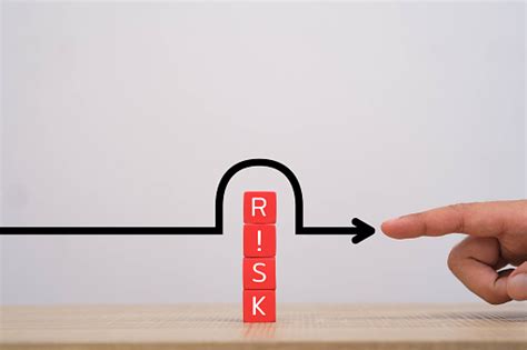 Risk라는 철자가 새겨진 나무 블록을 손가락으로 겨냥하여 위험을 극복하는 개념으로 비즈니스와 삶의 도전과 전략적 솔루션을 상징합니다 가까이 옴에 대한 스톡 사진 및 기타