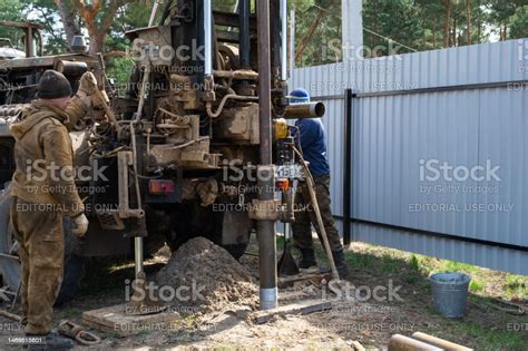 차에 드릴링 리그를 가진 노동자의 팀은 지상에 있는 물을 위한 지하수 우물을 뚫고 있습니다 금속 케이싱 파이프를 땅에 삽입 개별 식수 공급 장치 설치 2022년 6월 28일