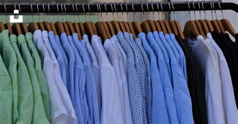 흰색 파란색과 회색 옷이 갈색 나무 선반에 매달려 있습니다 사진 Unsplash의 무료 스타일 이미지