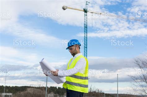 건설 현장에서 청사진을 들고 있는 건축가 또는 엔지니어 보호 복을 입고 푸른 하늘 위에 배경에 크레인 작업 개념입니다 백라이트 개념에 대한 스톡 사진 및 기타 이미지