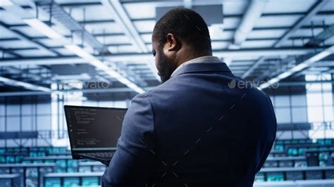 Programmer In Data Center Doing Yearly Maintenance Checkup Using Laptop