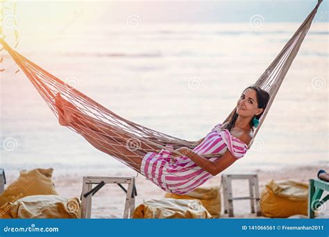 Cute Girl With A Smile Relaxes Lying In A Hammock On The Background Of