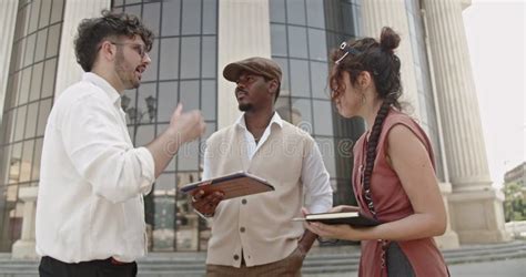 A Group Of Young Professionals Brainstorms Outside An Office Building Focusing On Creativity