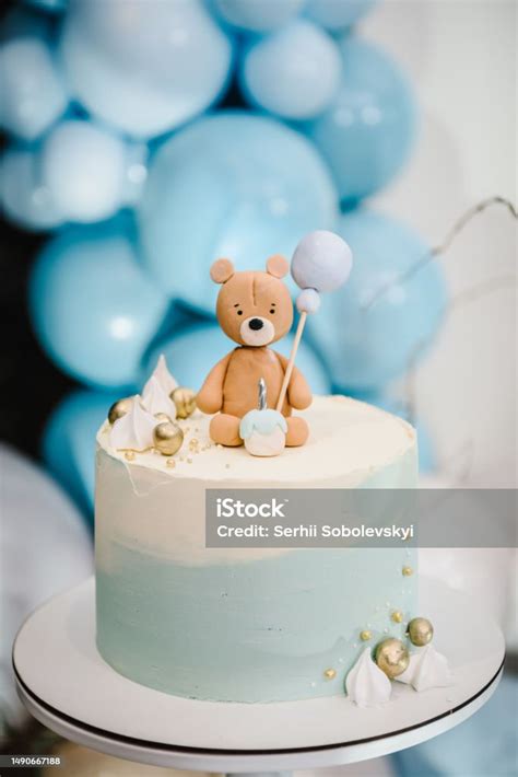 배경에 파란 풍선에 생일 케이크 피규어 곰이 있는 트렌디한 케이크는 소년을 위해 금색 장식을 장식했습니다 베이비 샤워 축하 세례 개념입니다 생일 파티에서 맛있는 리셉션 근접