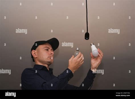 A Man Changes An Incandescent Lamp To An LED Lamp Stock Photo Alamy
