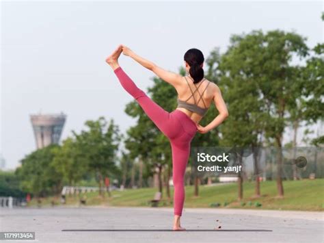 스포츠웨어 빨간 바지 야외에서 요가를 연습하는 건강 한 여성의 뒷모습 큰 발가락 포즈에 손을 뻗어 운동 우티타 하스타 파단 구스타사나에 서 공원 배경전체 길이 건강한 생활