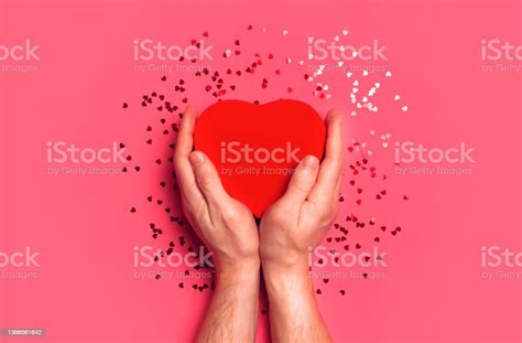 발렌타인 데이 컨셉 빨간 하트 모양의 선물 상자를 들고 있는 남자의 손 분홍색 배경 상단 뷰 플랫 레이에 색종이 사랑 생일 선물 어머니의 날 3 월 8 일 휴일 배경의