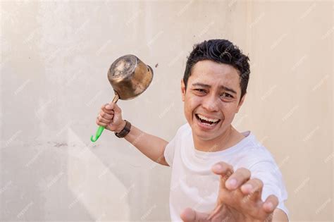 Premium Photo Indonesian Men Pose Hitting Hold The Pan Wear White Tshirt