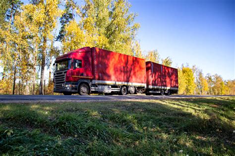 세미 트레일러가 장착 된 새로운 빨간색 트럭은 많은 벌크화물을 운송합니다 가을의 숲을 배경으로 시골길에서 화물 운송 텍스트 공간 복사 0명에 대한 스톡 사진 및 기타 이미지