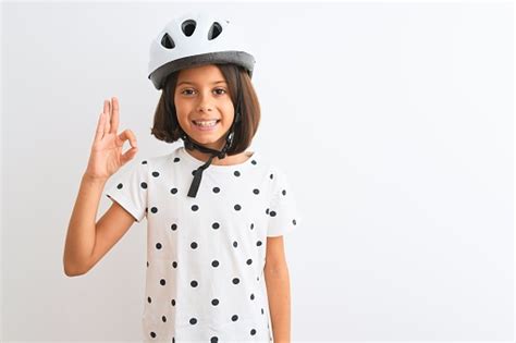 손과 손가락으로 확인 기호를하고 긍정적 인 미소 고립 된 흰색 배경 위에 서 보안 자전거 헬멧을 착용 아름다운 아이 소녀 성공적인 식입니다 건강한 생활방식에 대한 스톡 사진