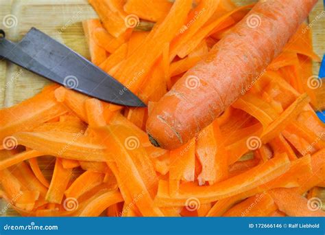 Close Up Of Isolated Raw Fresh Carrot Cut In Stripes With Blade Of Japanese Kitchen Knife On