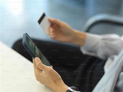 스마트폰으로 온라인 결제를 하는 동안 신용 카드를 들고 있는 사업가의 측면 모습 사진 Unsplash의 사진술 이미지