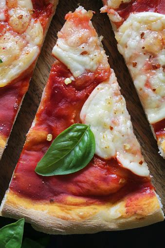 얇게 썬 갓 구운 수제 마르게리타 피자 골든 버팔로 모짜렐라 치즈 서클 풍부한 토마토 마리나라 소스 신선한 바질 잎 토핑 나무 도마 배경 높은 전망 0명에 대한 스톡 사진