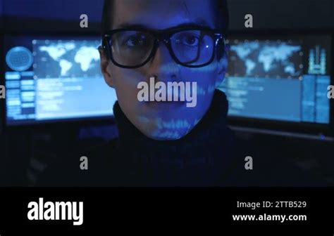 Portrait Of Hacker Programmer In Glasses Looks At Camera While Blue
