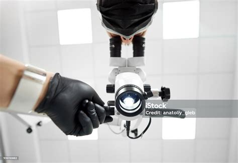 흰색 밝은 치과 사무실에서 전문 치과 장비의 도움으로 현미경에서 보이는 검은 고무 장갑을 끼고 남자 치과의 Upwardview 치과 장비에 대한 스톡 사진 및 기타 이미지