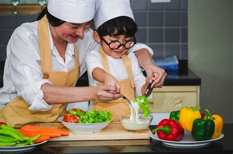 아시아 여자 젊은 어머니 와 아들 소년 요리 샐러드 엄마 슬라이스 야채 음식 아들 시식 샐러드 드레싱 야채 당근과 토마토 피망 행복 한 가족 요리 음식 즐거움 라이프 스타일