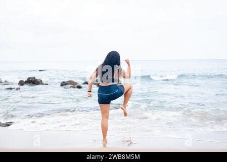 Fitness Woman Standing Doing Leg Exercises On The Beach Sand With Her