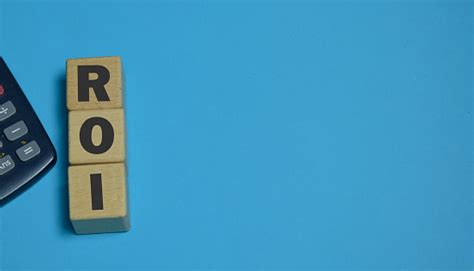 투자 수익 좋은 Roi와 돈 버는 개념 계산기로 나무 블록을 정육면하고 회색 글자로 만든 구성으로 Roi라는 텍스트를 작성하십시오 파란색 배경으로 격리되어 있습니다 개념에